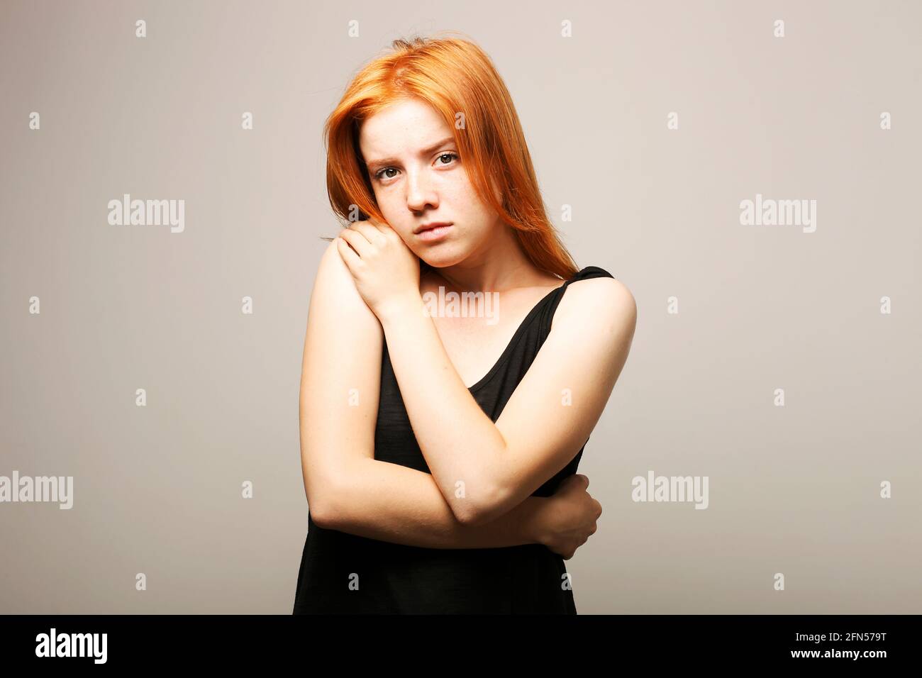Beautiful fragile redheaded young woman in the dark. Sad frightened ...