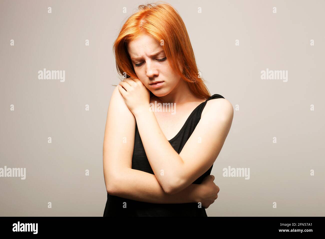 Beautiful fragile redheaded young woman in the dark. Sad frightened ...