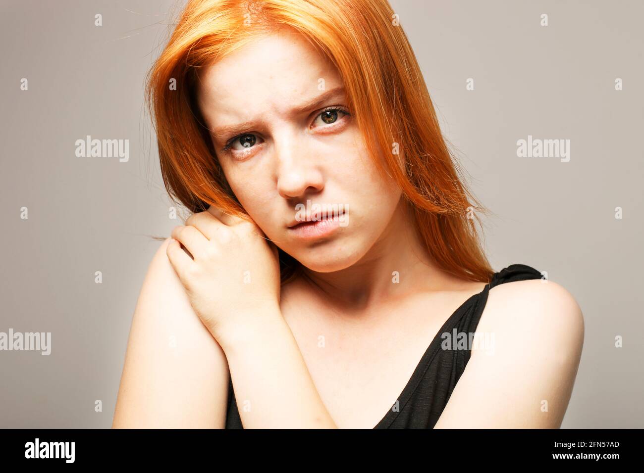 Beautiful fragile redheaded young woman in the dark. Sad frightened ...