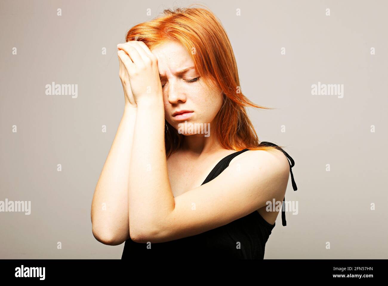 Beautiful fragile redheaded young woman in the dark. Sad frightened ...
