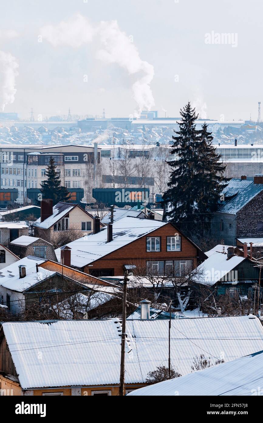 Winter town view of houses with snow-covered roofs and an industrial ...