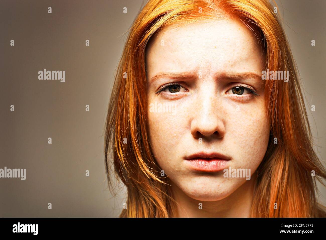 Beautiful fragile redheaded young woman in the dark. Sad frightened ...