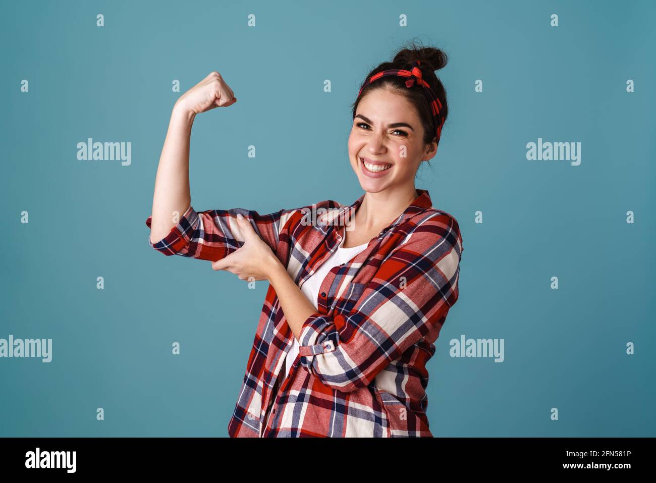 Happy beautiful brunette girl smiling and showing her bicep isolated ...