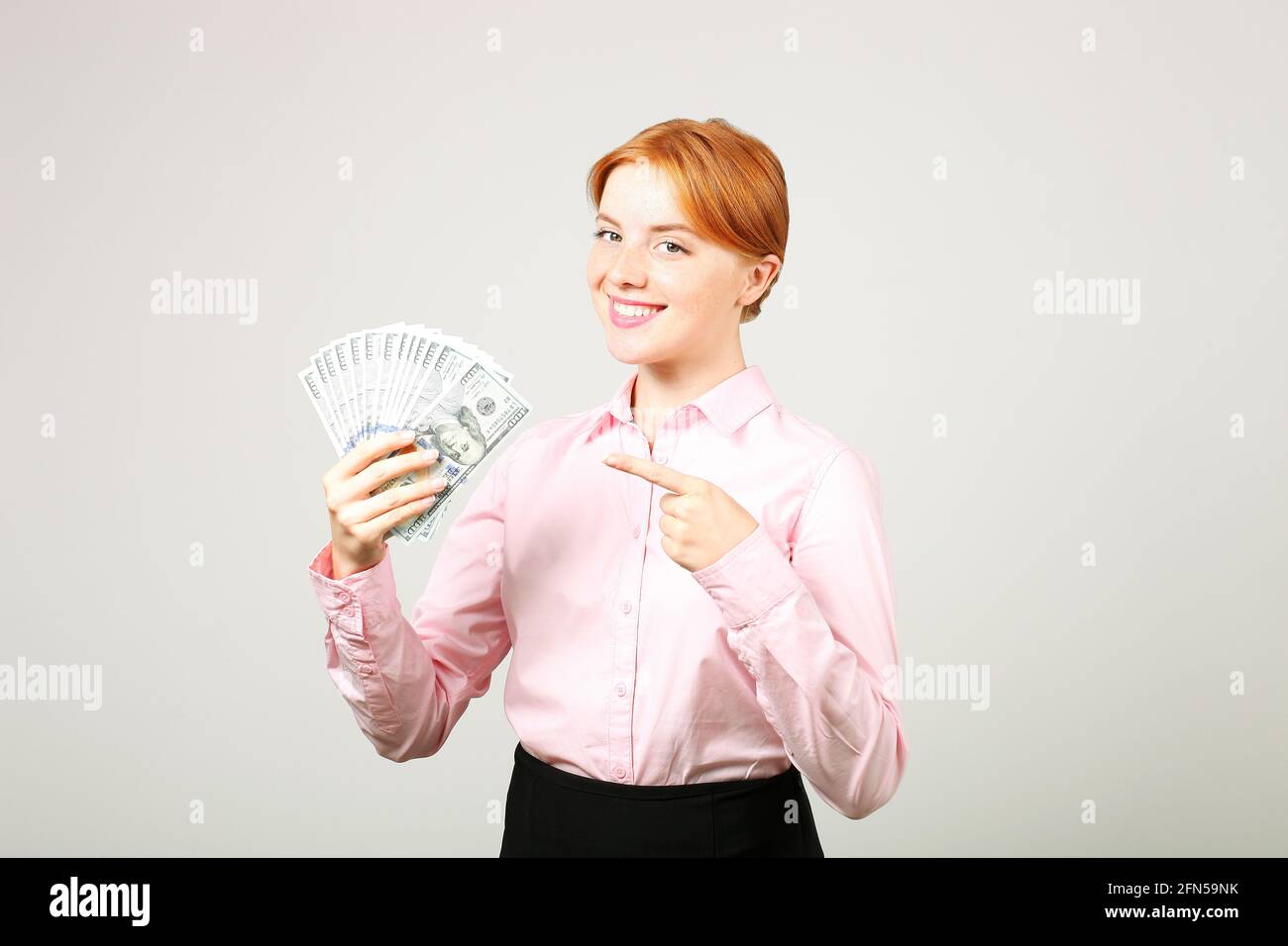 Young beautiful redhead woman pointing with index finger to fistful of ...