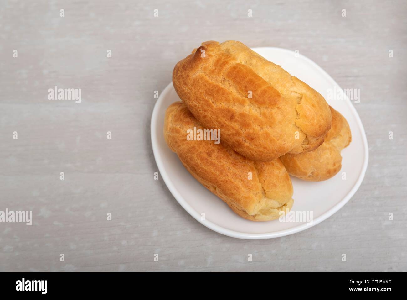 Air eclairs on white saucer. Close up, top view. Profiteroles, puffs or ...