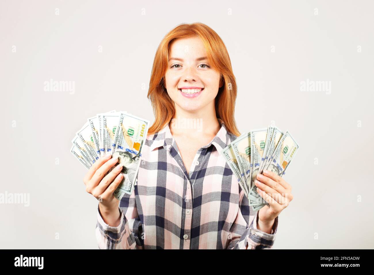 Portrait of young beautiful redhead woman with fistful of money holding ...