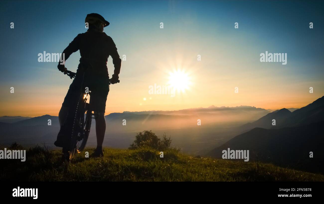 Wide shot, back view of silhouette sitting on a mountain bike, enjoying ...