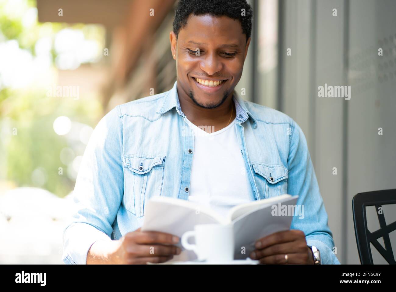 Man reading a book at coffee shop Stock Photo - Alamy