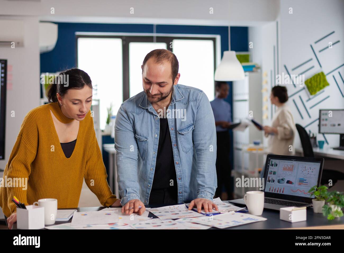 Project manager and assistant working together on charts for new ...