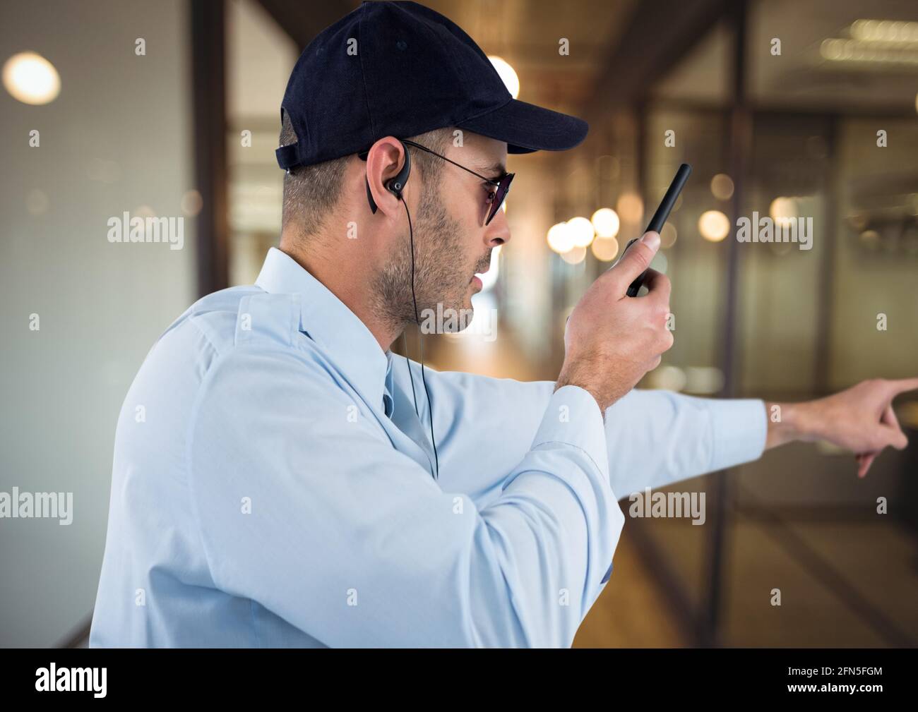 Composition of male security guard using walkie talkie holding hand out ...