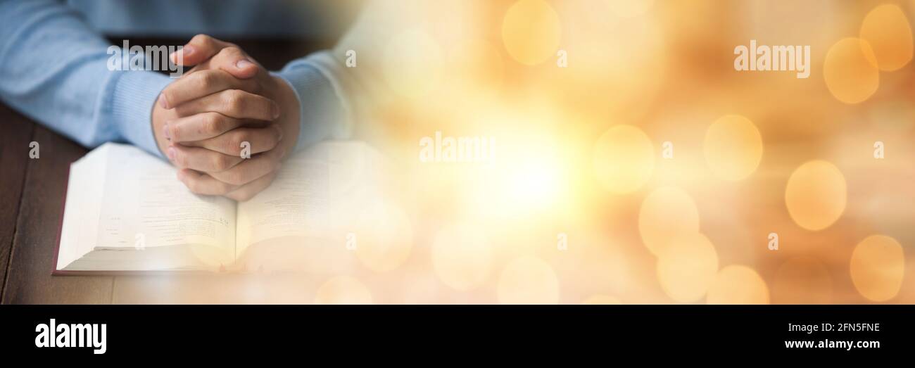 Composition of midsection of man praying with holy bible with glowing ...