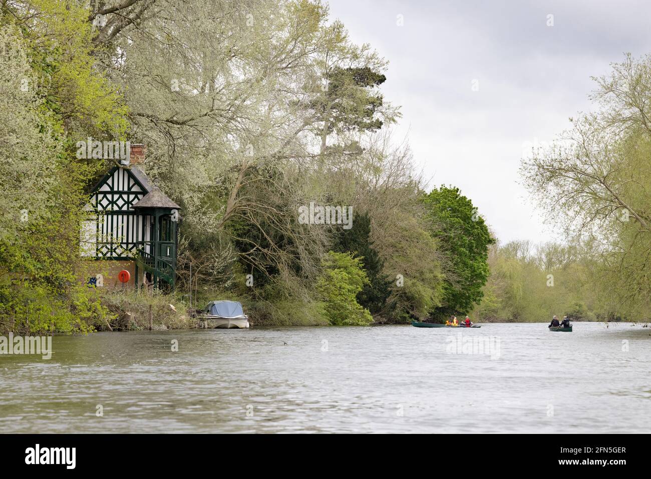 River Thames view; Boathouse, boat and canoes in a river landscape; The ...