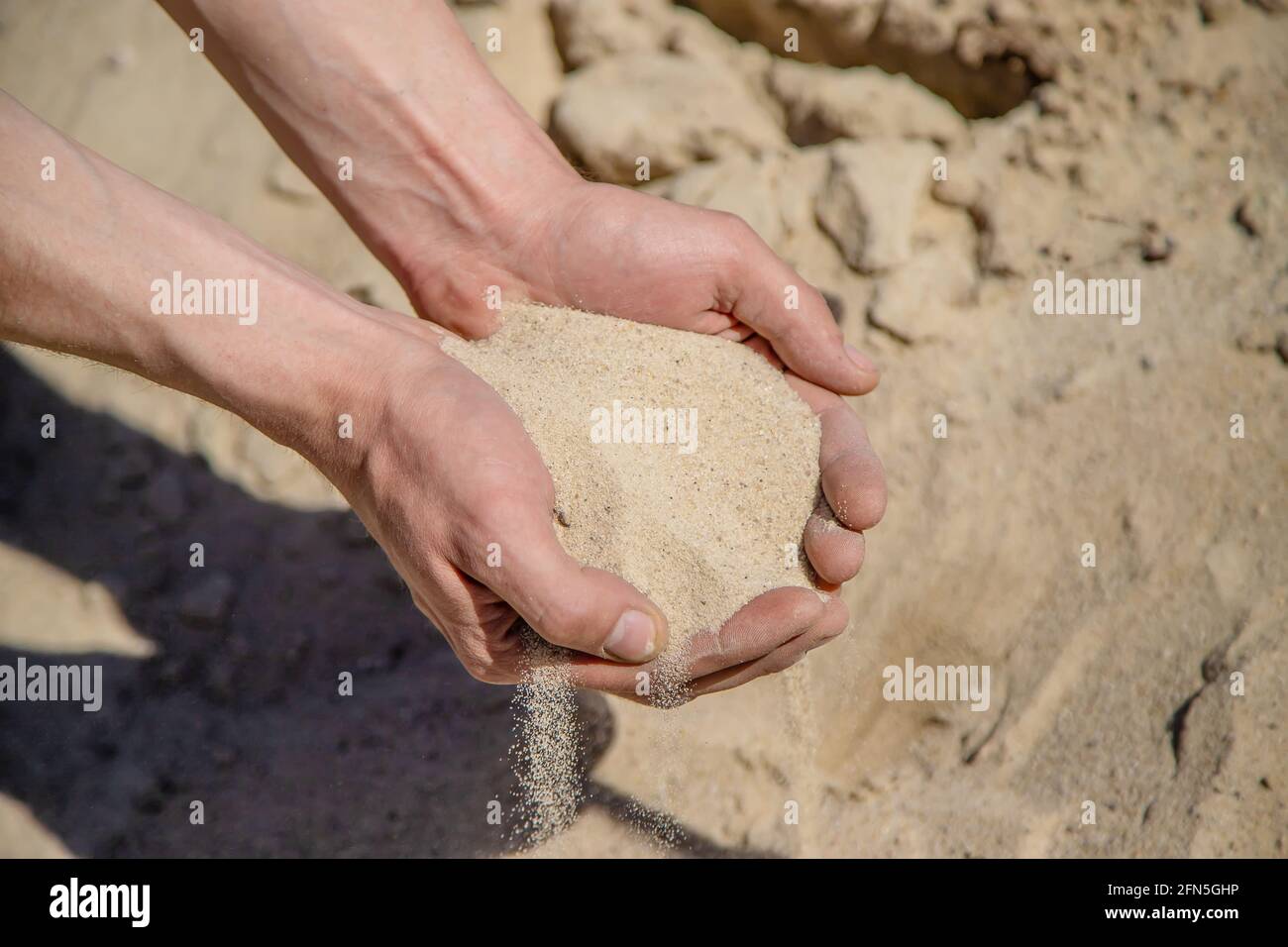Man holding sand in his hands Stock Photo - Alamy