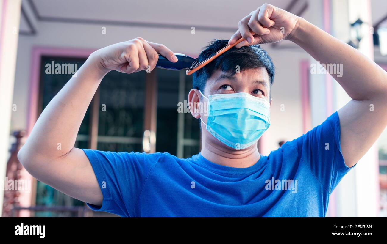 Man wear face mask and cutting hair personally himself with machine ...