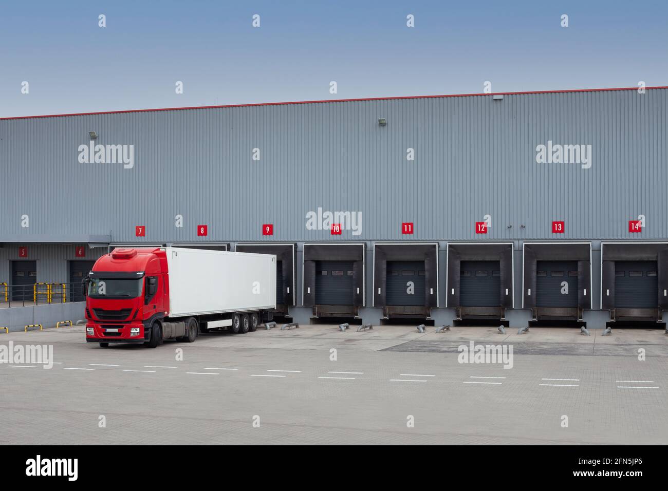 Red truck while loading in a big distribution warehouse. Copy space ...