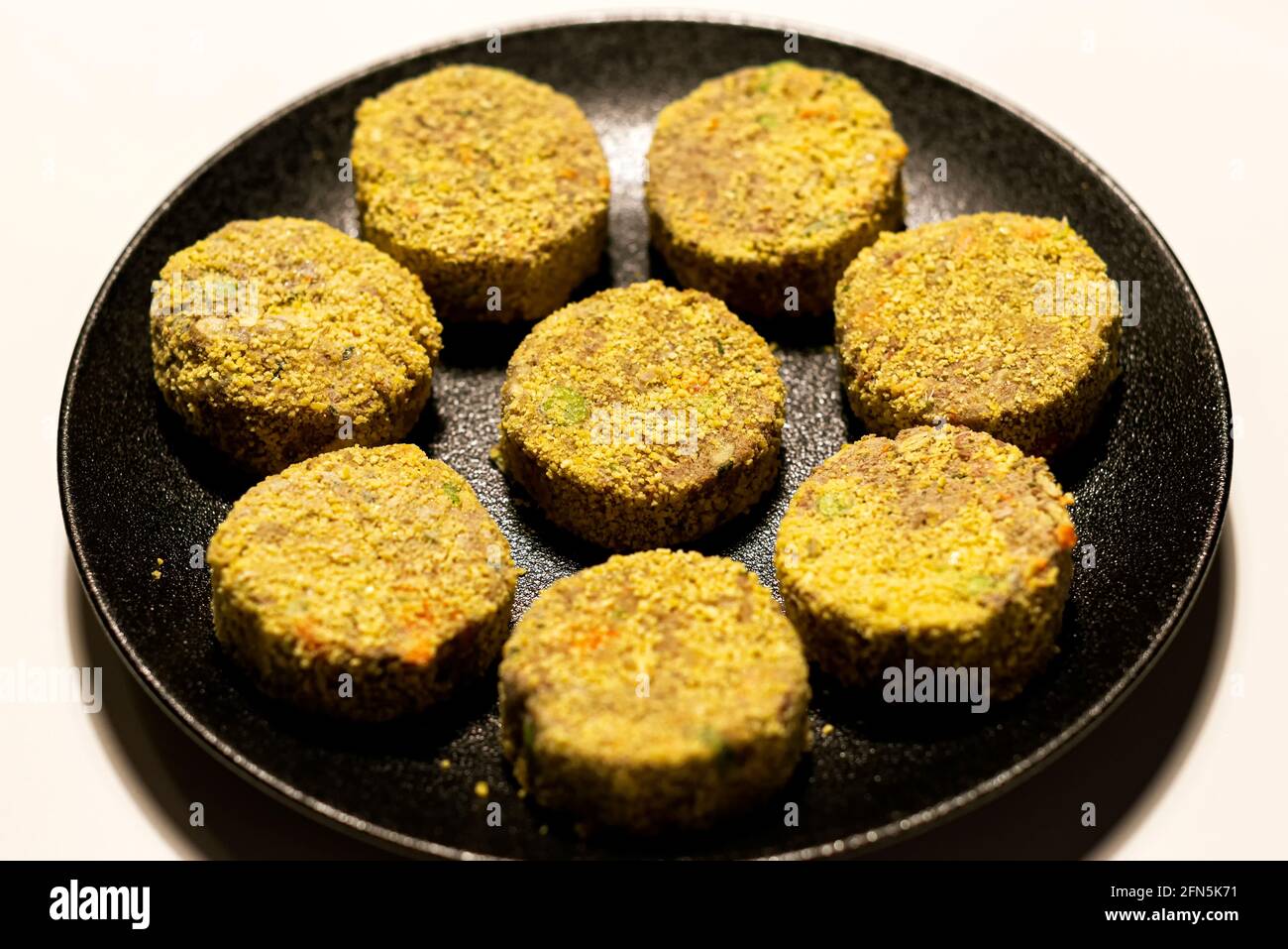 Frozen veggie nuggets with lentils and greens on a black plate Stock ...