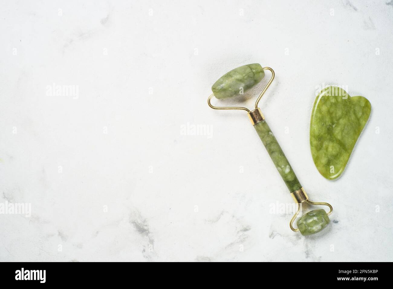 Jade roller and gua sha stone massager for face Stock Photo - Alamy