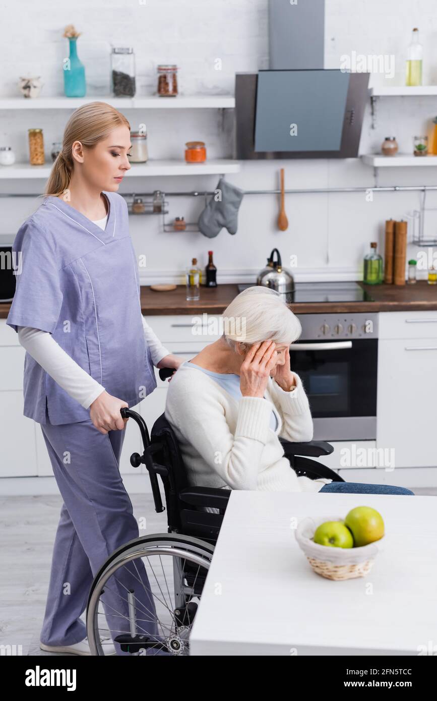 young social worker near handicapped senior woman sick on dementia ...