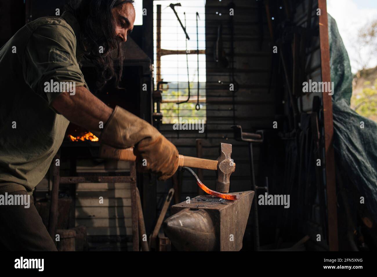 Blacksmith working a piece of red-hot steel with a sledgehammer Stock ...