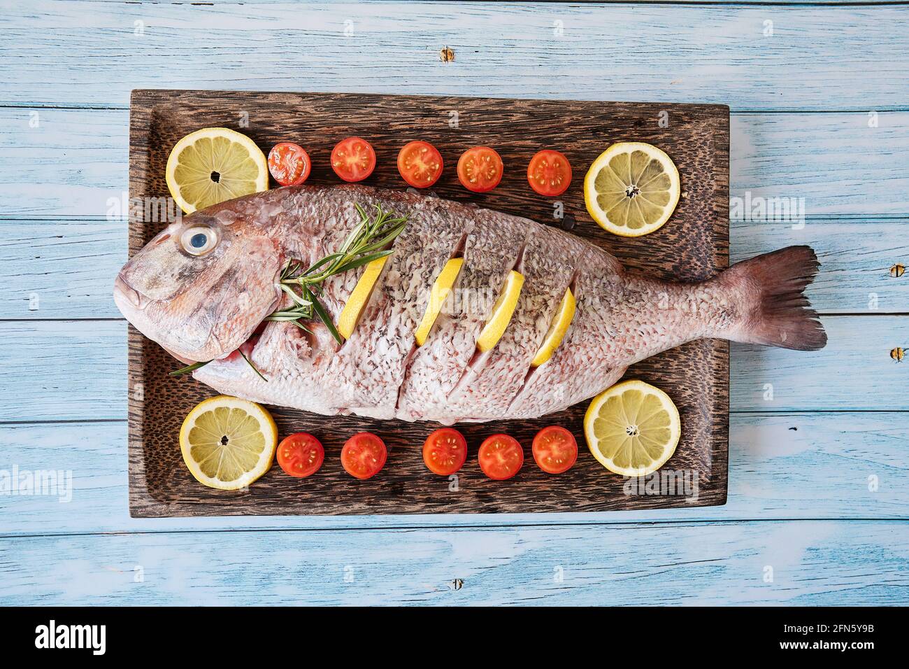 Fish tray to bake in the oven with tomatoes and lemons Stock Photo - Alamy