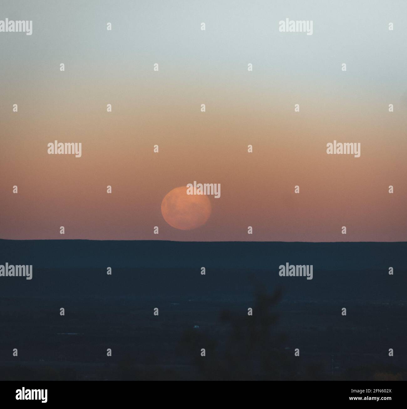 full moon appearing on the horizon Stock Photo - Alamy