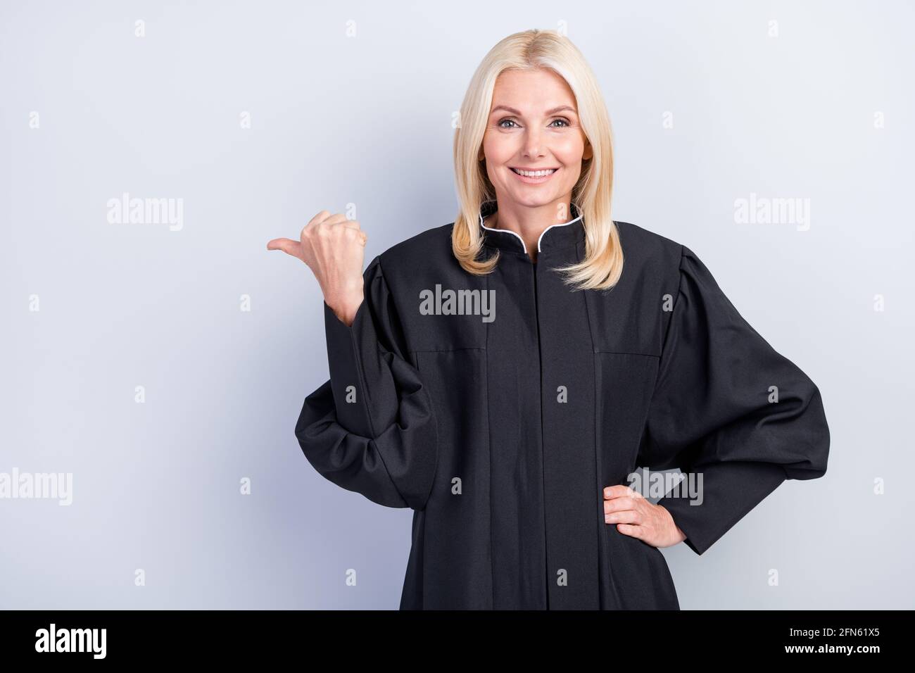 Portrait of attractive trendy cheerful woman judge pointing thumb aside ...