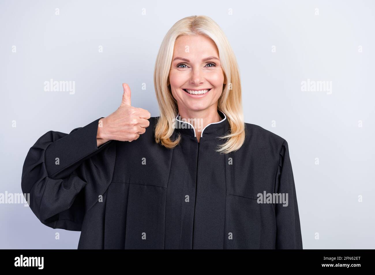 Portrait of attractive cheerful woman judge showing thumbup solution ...