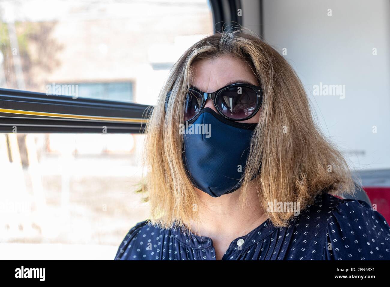 Portrait of Latin American woman on a TTC bus wearing a protective face ...