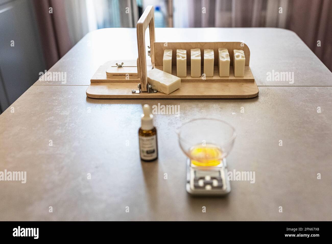 A soap-maker weighs aromatic oils for making cosmetics on a kitchen ...