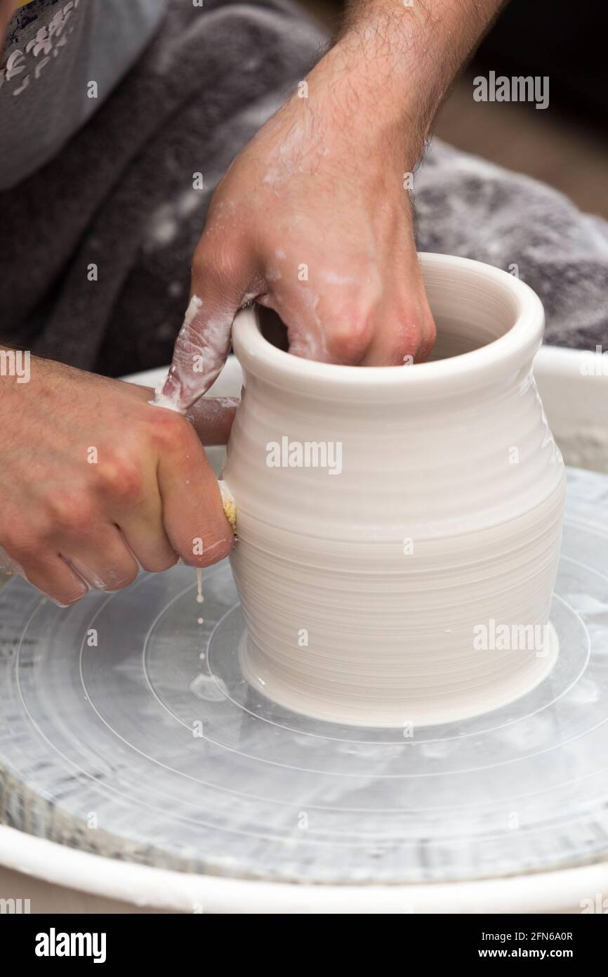 Potter / potters hands skilfully hand throwing a ceramic thrown clay ...