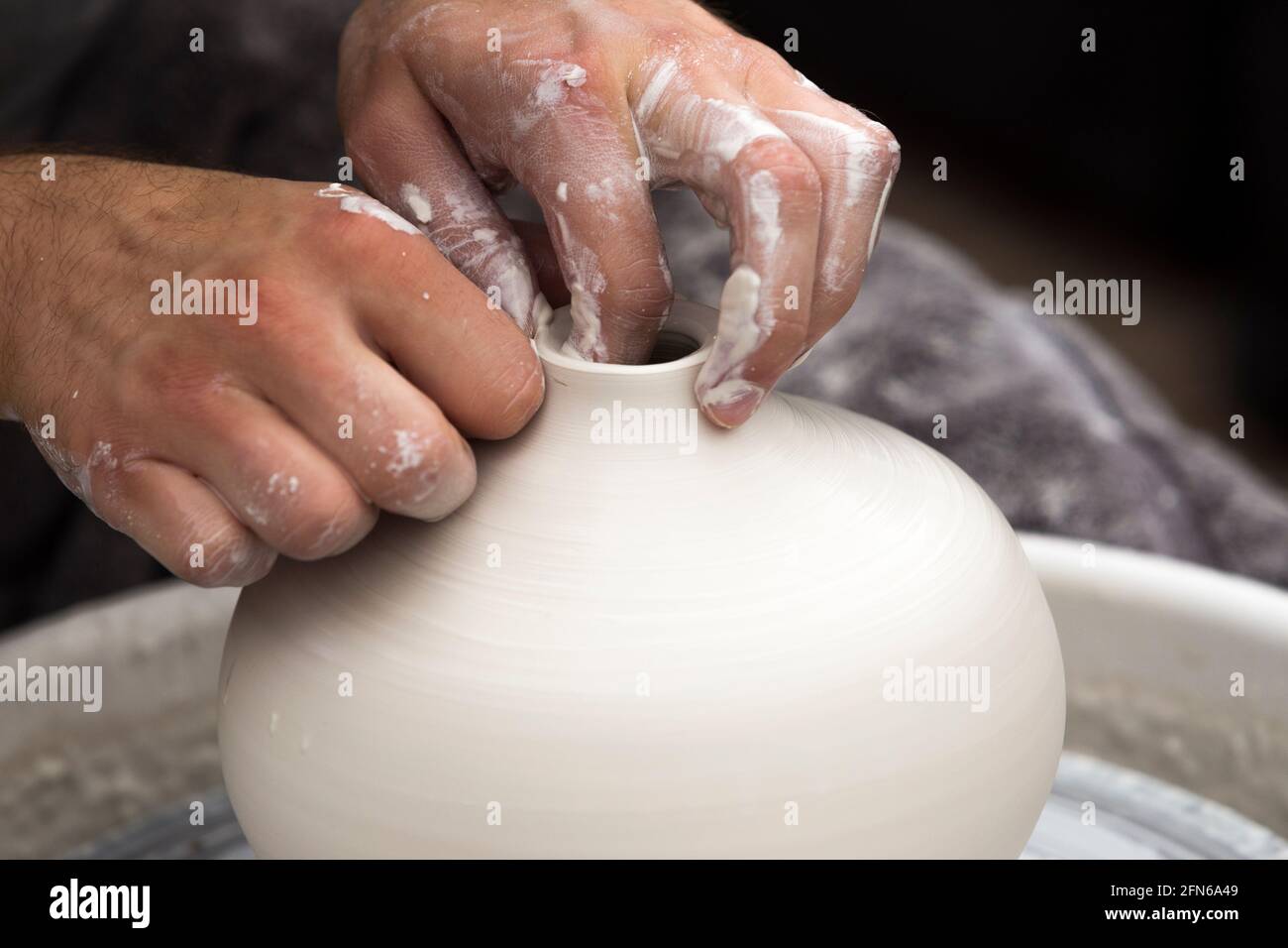 Potter / potters hands skilfully hand throwing a ceramic thrown clay ...