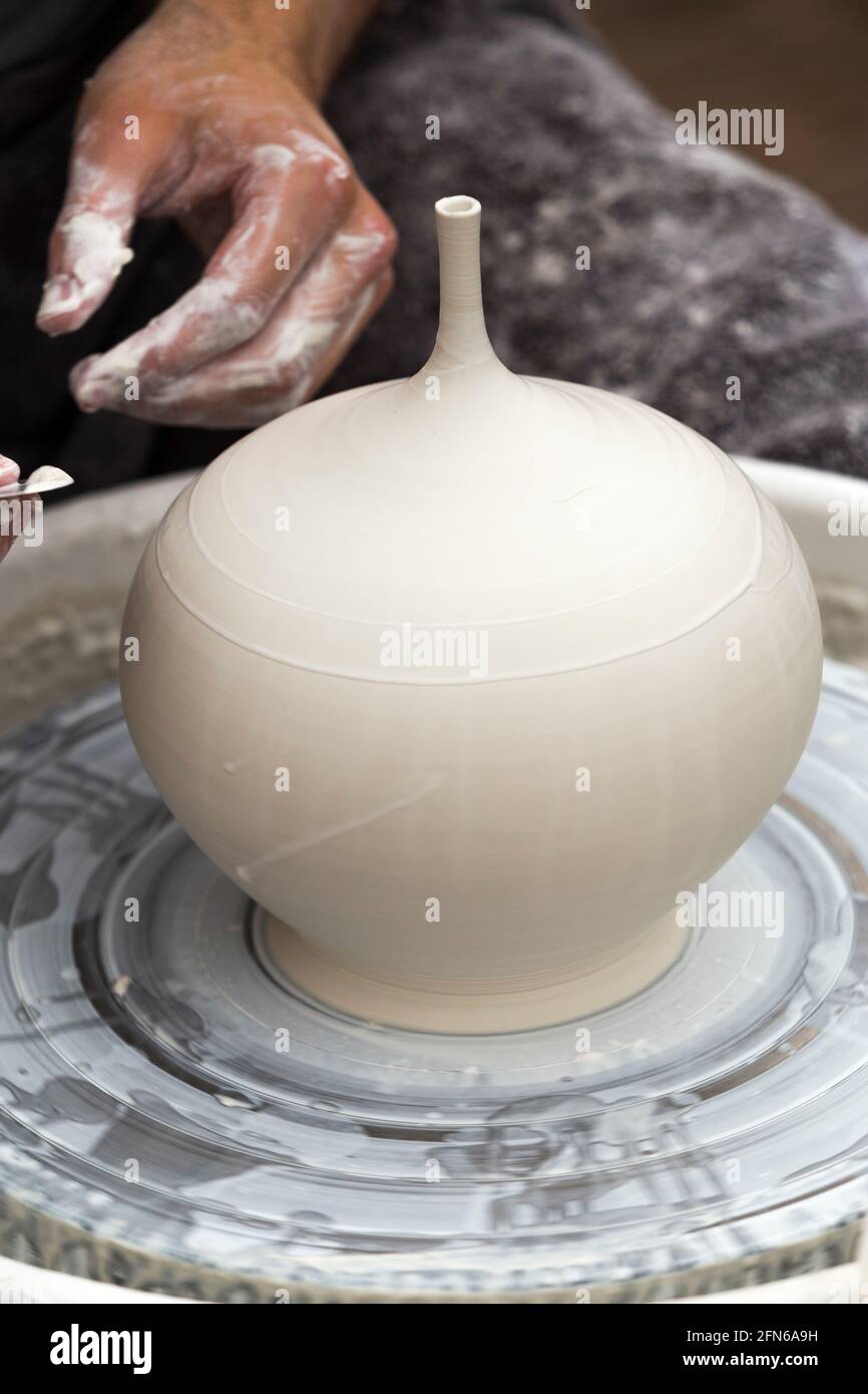 Potter / potters hands skilfully hand throwing a ceramic thrown clay ...