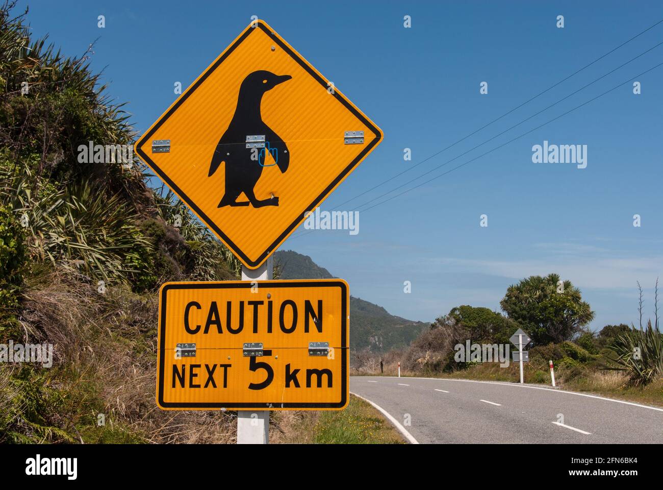 Caution penguins crossing next 5 km! Warning sign at a coastal road on ...