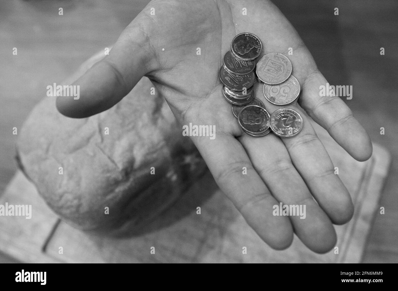 Last money to buy bread. A loaf of bread and the hand of an old man ...