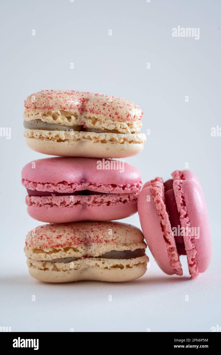 A small stack of French macarons in pink and yellow with one macaron on ...