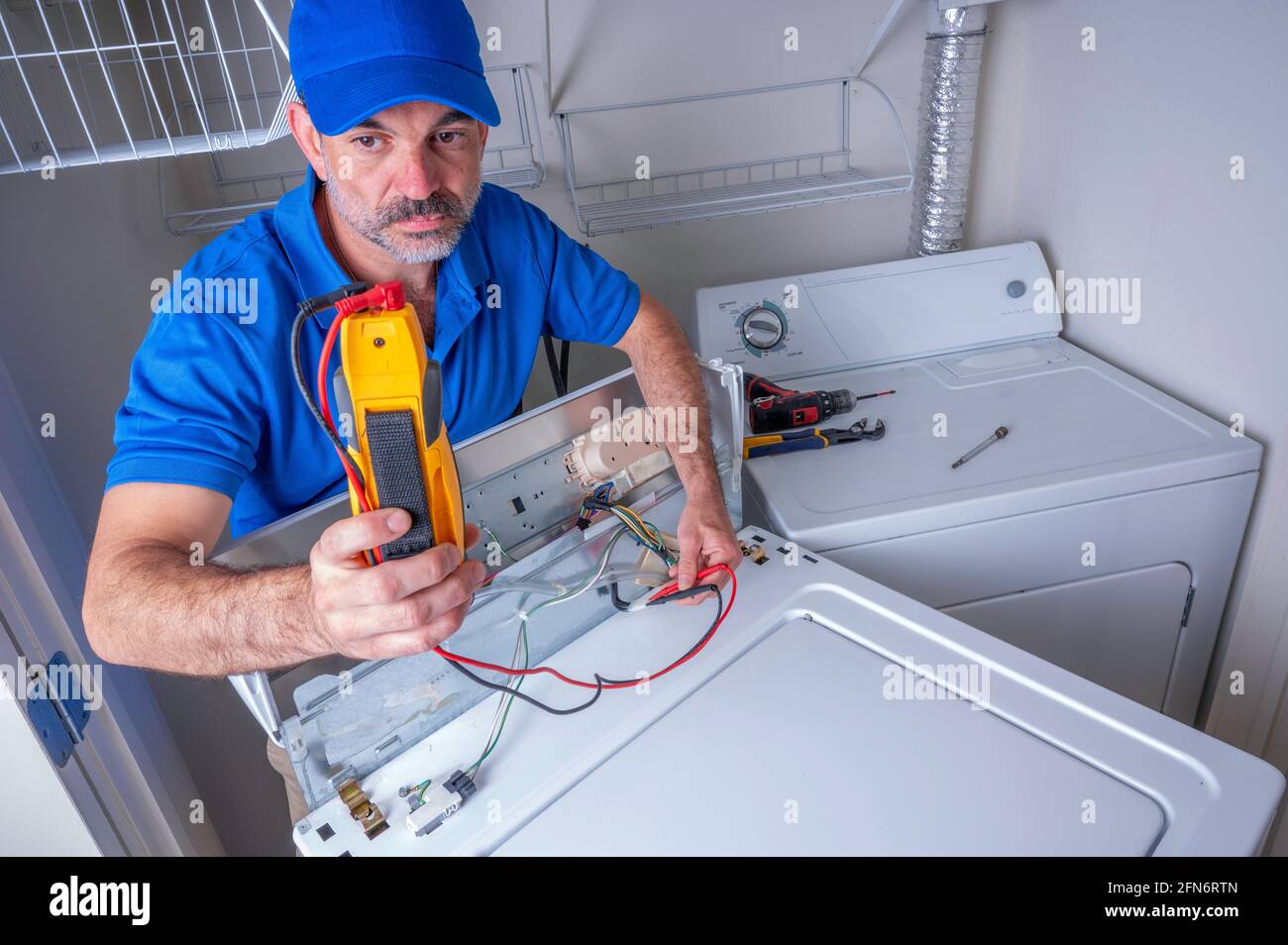 An appliance technician testing circuits on a residential washing ...