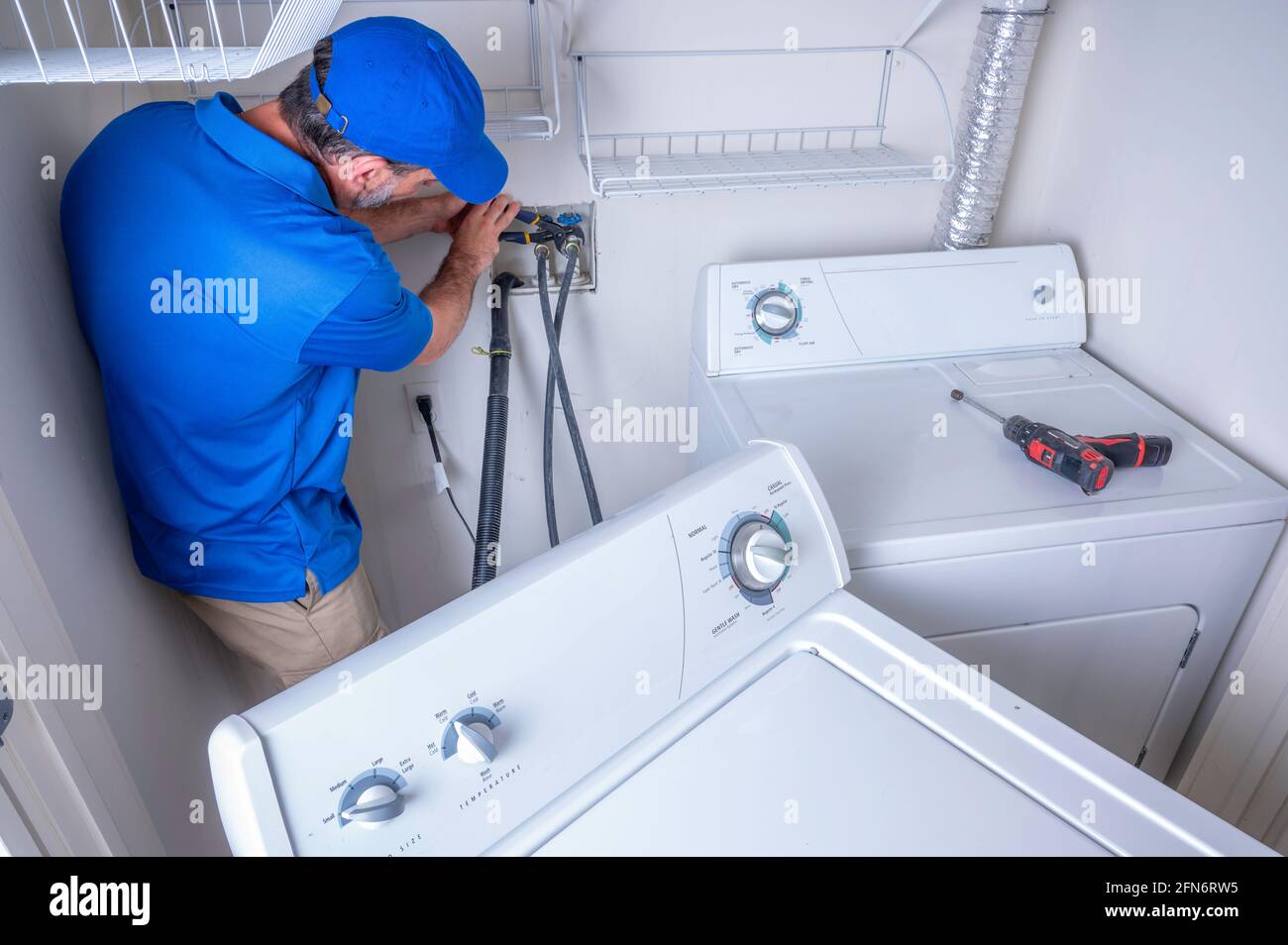 Plumber installing a residential washing machine, hooking up the water ...