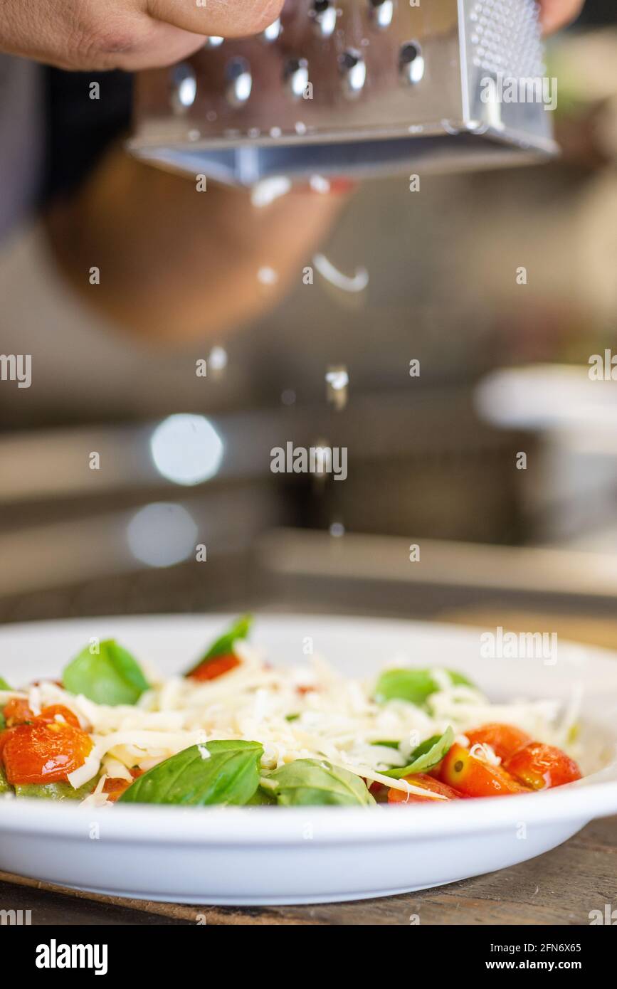 hands grating parmesan cheese over dish of pasta Stock Photo - Alamy