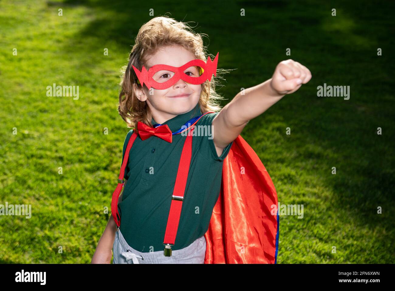 Superhero child against spring green field outdoor. Freedom and ...