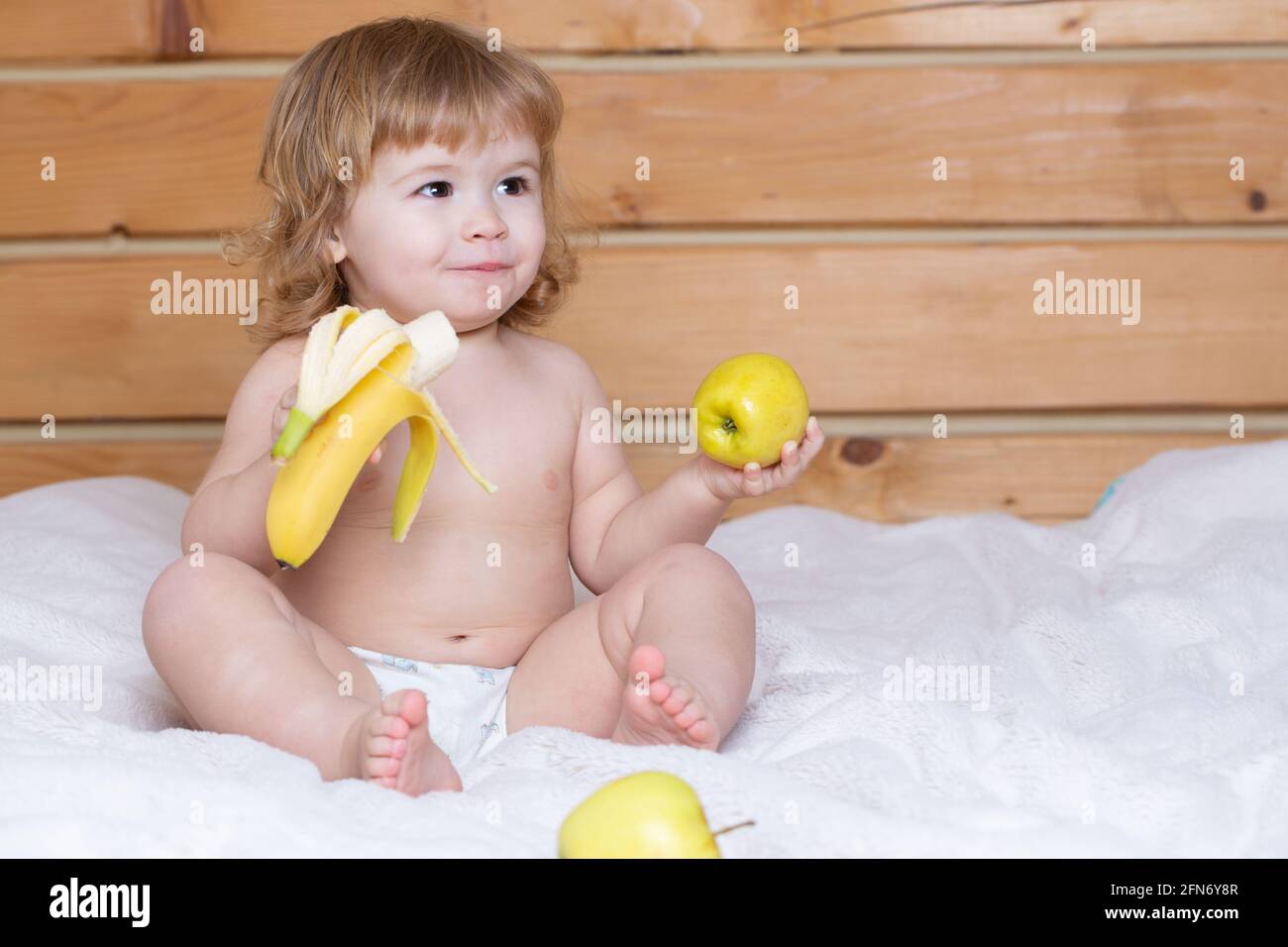 Kid with fresh fruit. Happy toddler eats apples and banana. Child ...