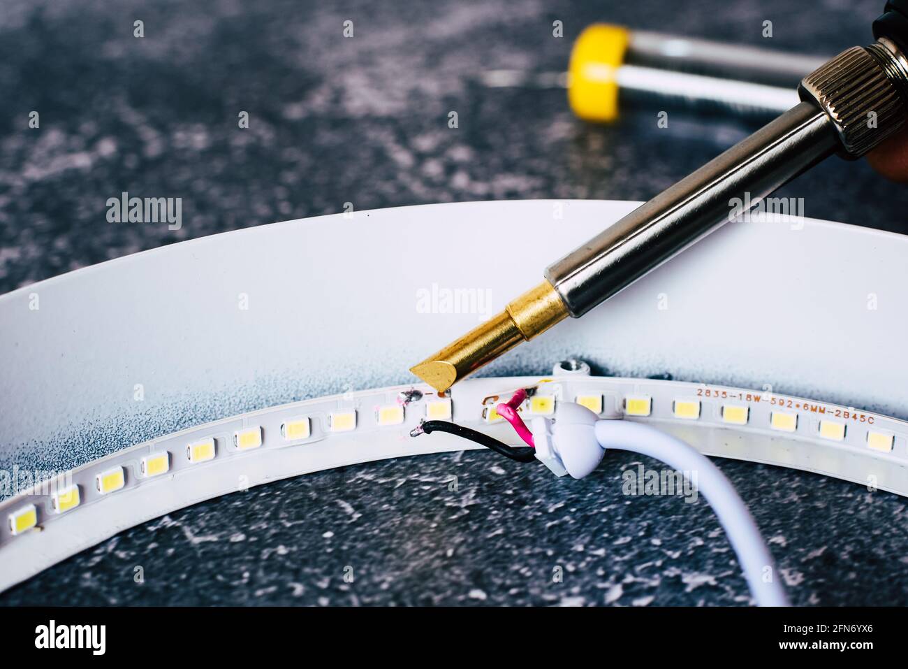 Detail of a tin soldering iron repairing a damaged led strip of lights ...