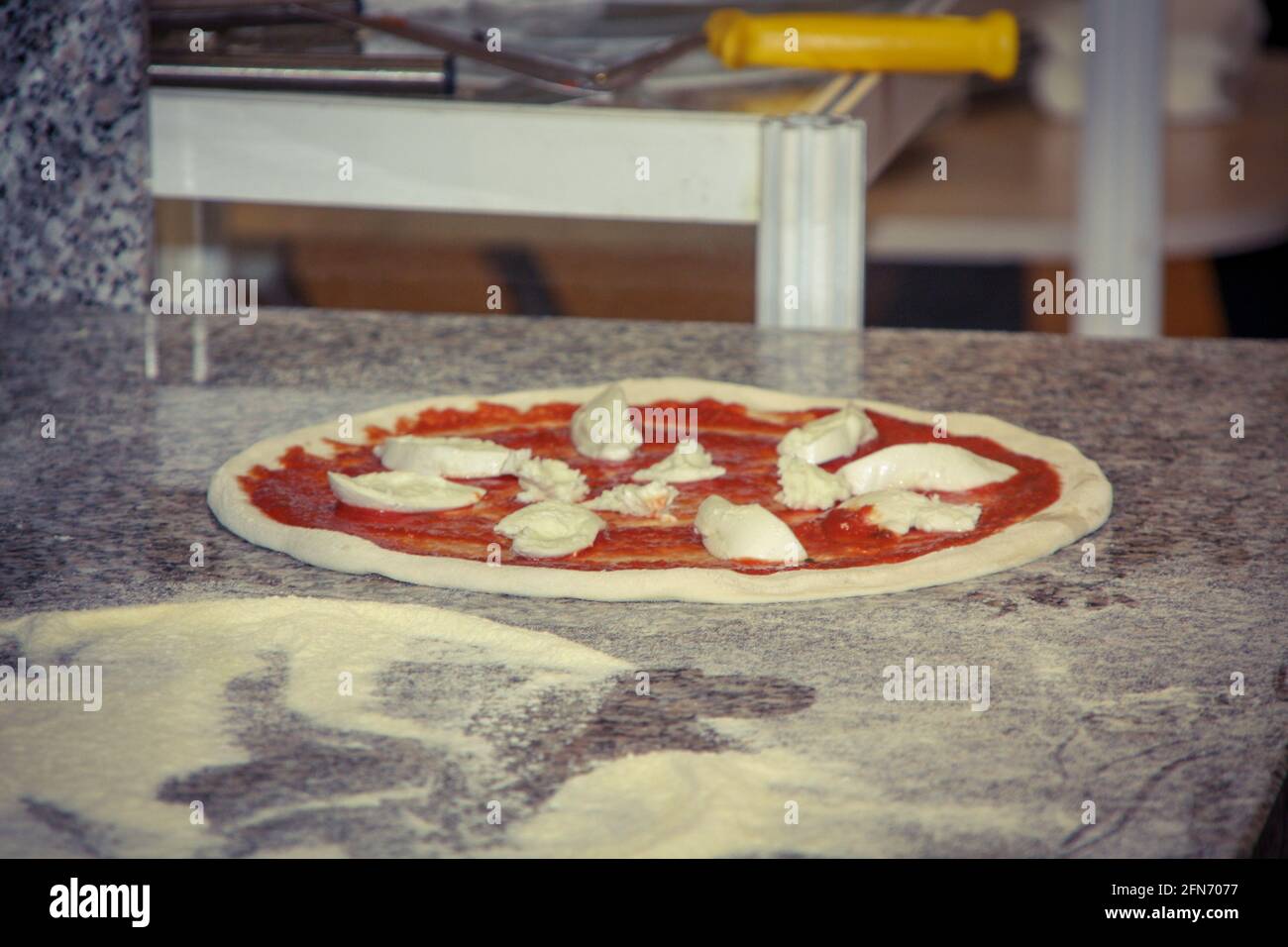 Selective focus of a raw pizza on a tile surface in a kitchen Stock ...