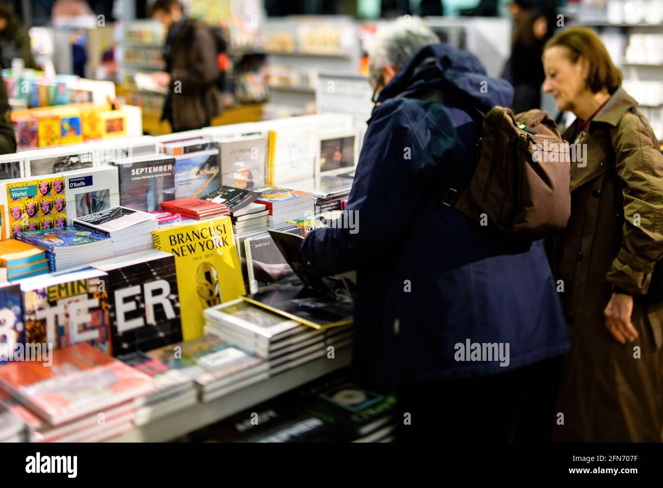 Rear view of two senior women buying shopping for books at library ...
