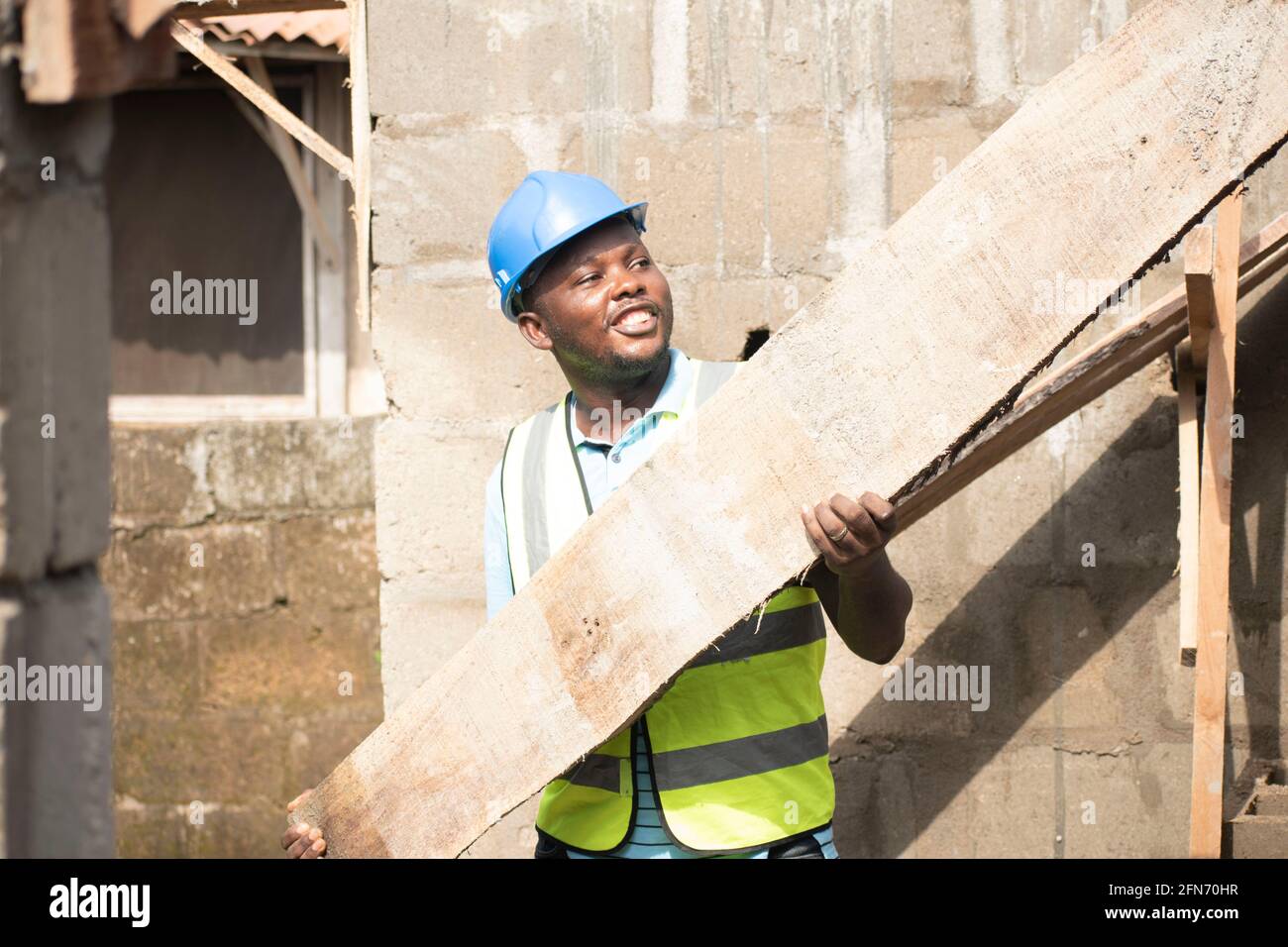 a carpenter carrying wood on site Stock Photo - Alamy