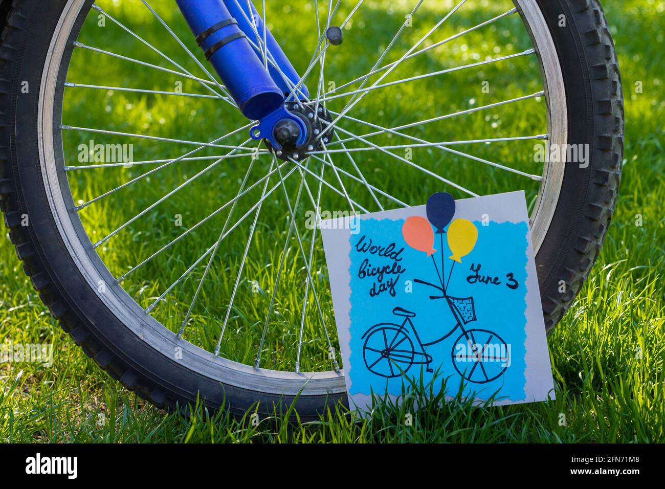 Handmade colored paper greeting card next to a bicycle wheel on grass ...