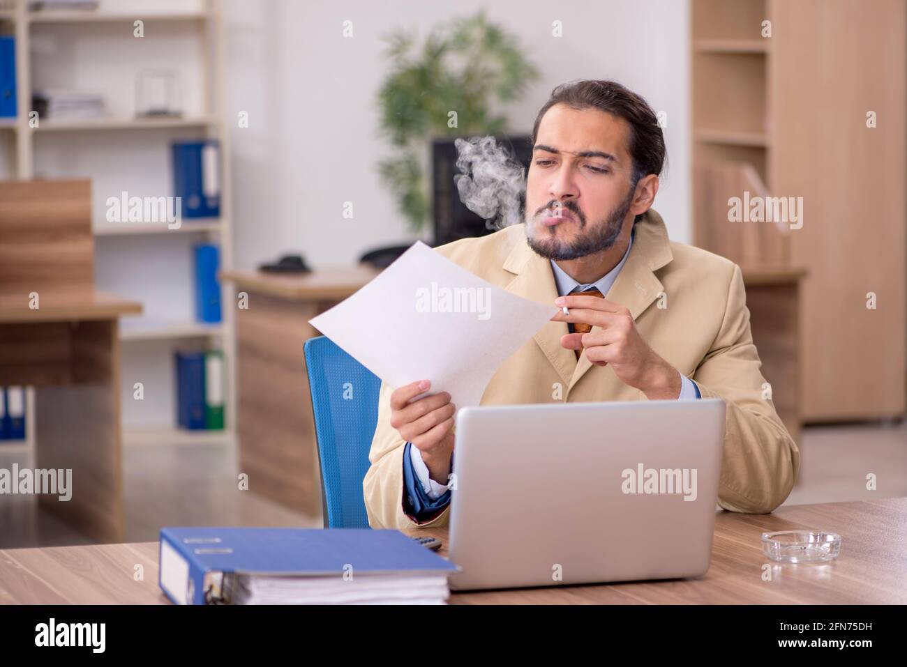 Sick cigarette addicted male employee working in the office Stock Photo ...