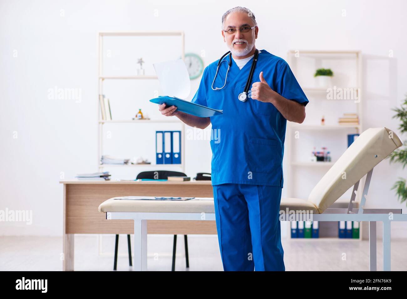Senior male doctor taking notes in the clinic Stock Photo - Alamy
