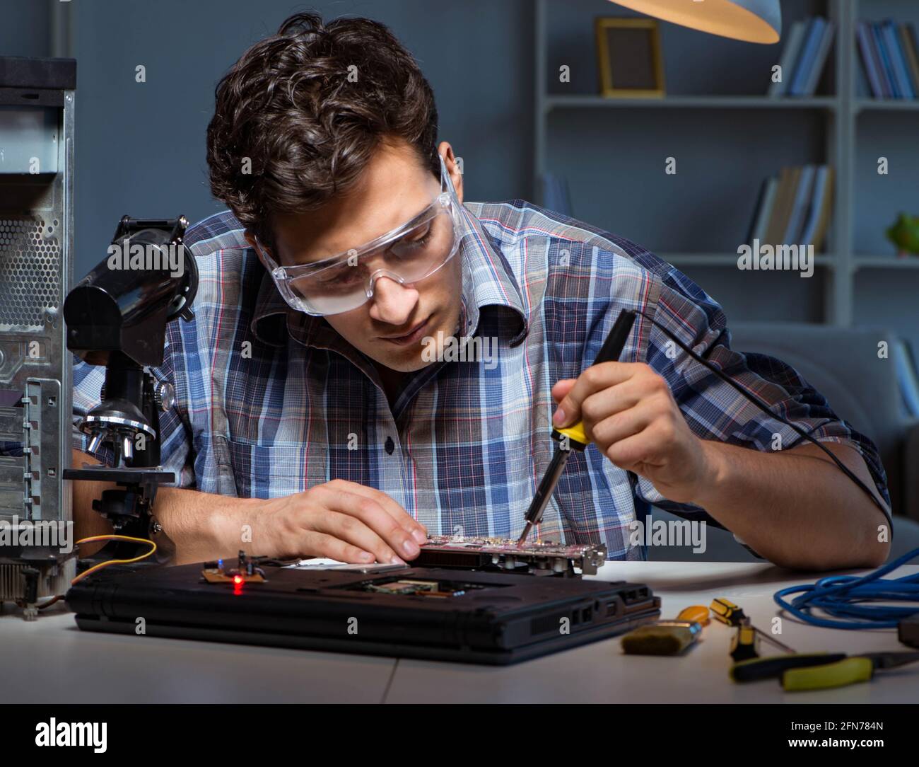 Young repair technician soldering electrical parts on motherboard Stock ...