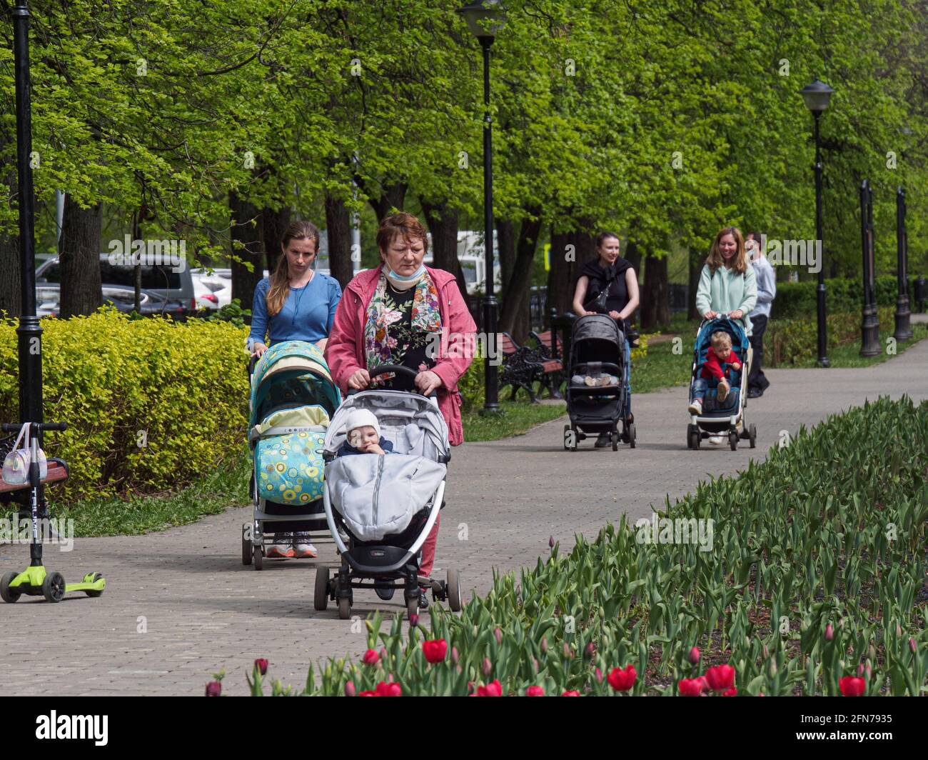 Women walk with their children in strollers along the spring boulevard ...