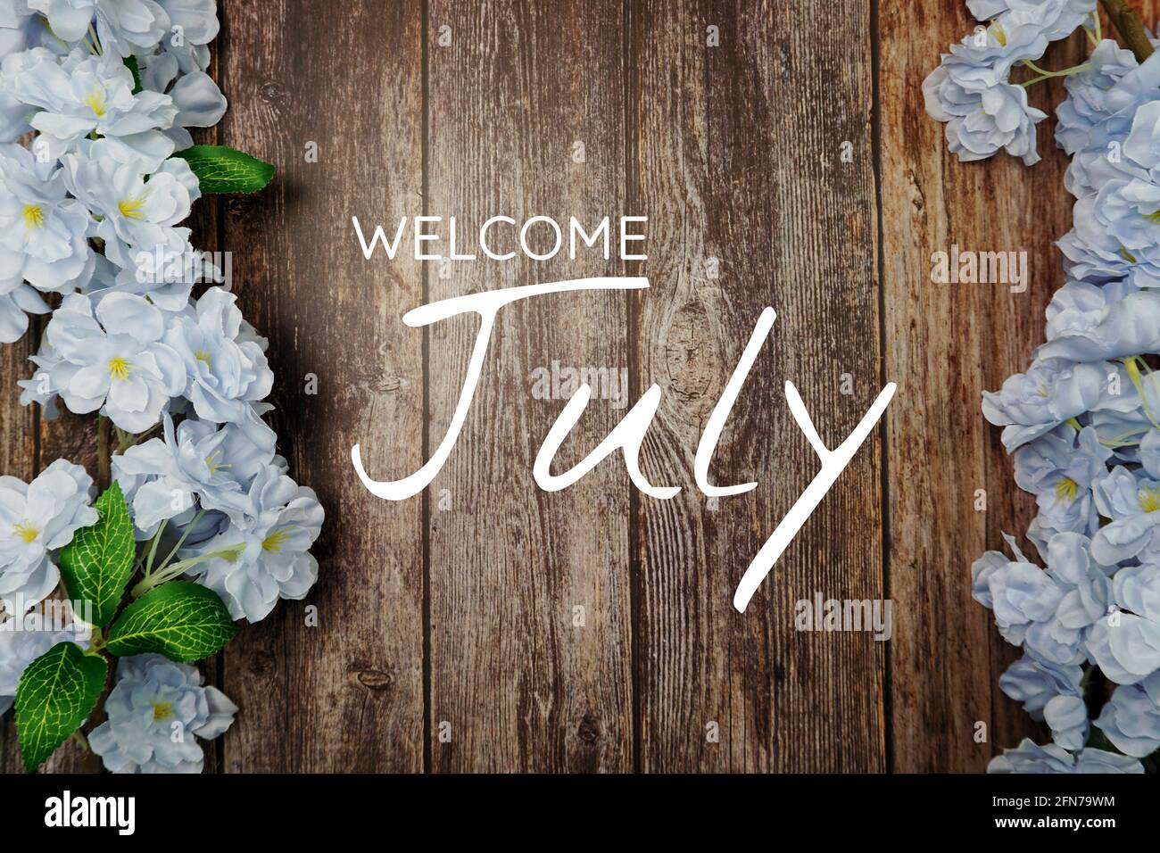 Welcome July text and blue flower decoration on wooden background Stock ...
